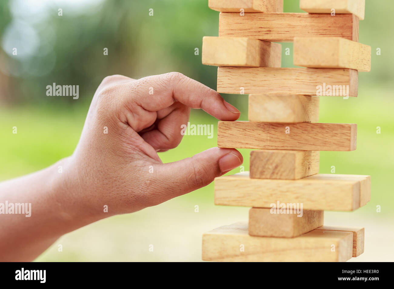 Close up hand holding blocks wood game (jenga) on blurred green ...