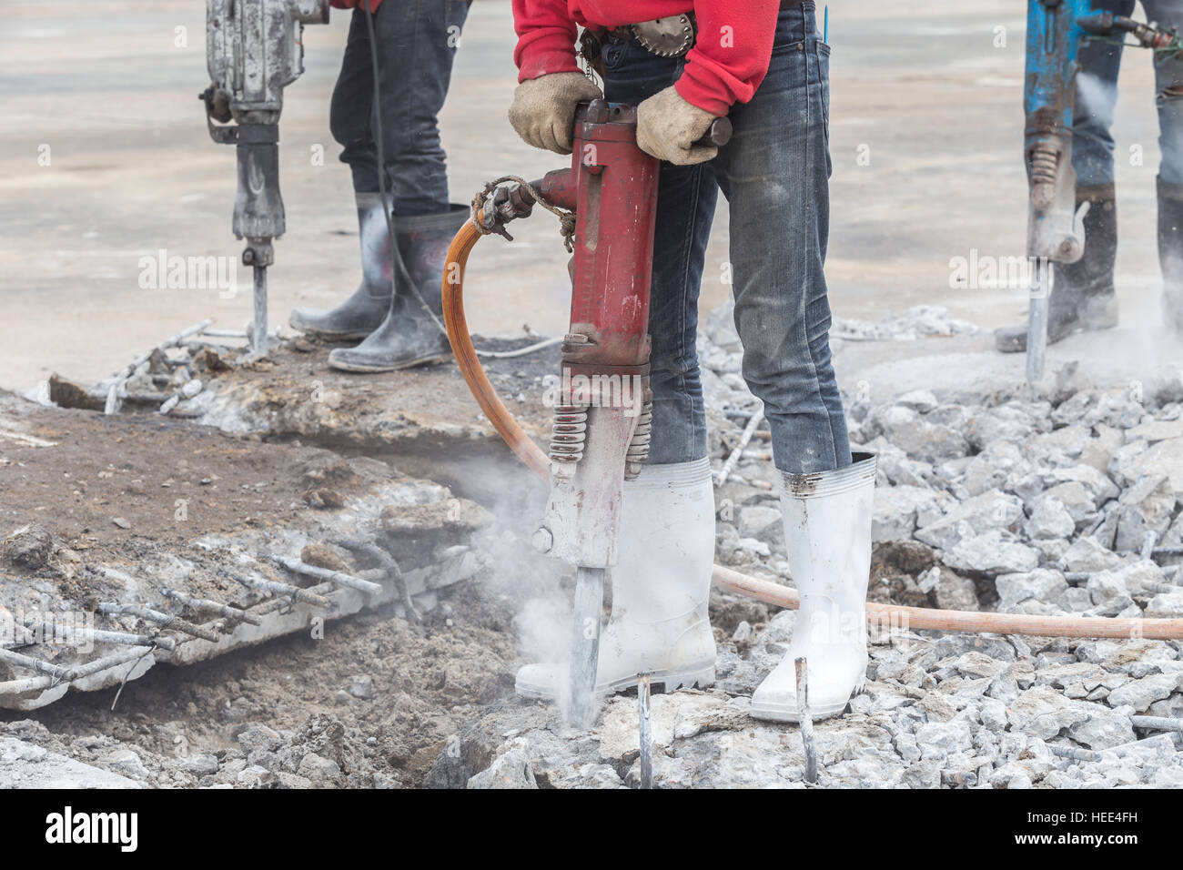 Construction worker removes excess concrete with drilling machine in ...