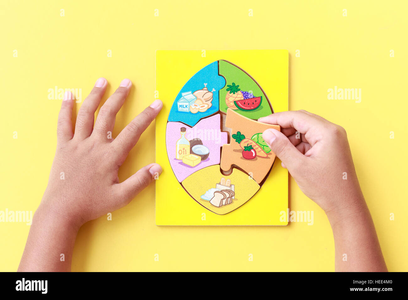 Close up hand of kid holding wooden jigsaw of the 5 food Groups. Child ...