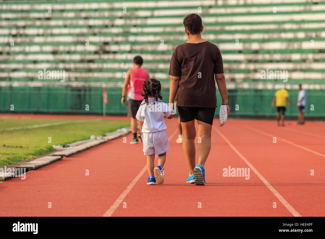 A mother holding her daughter hand and walking in running track Stock ...