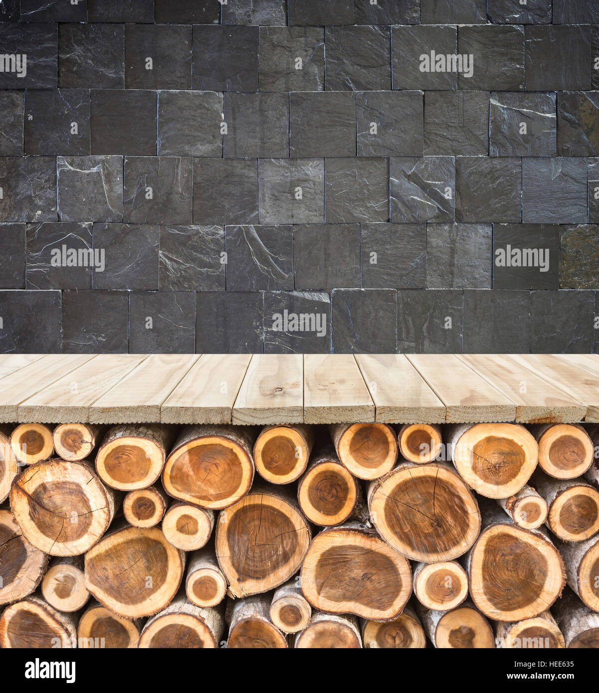 Empty top of wooden table or counter with pile wood log and stone wall ...