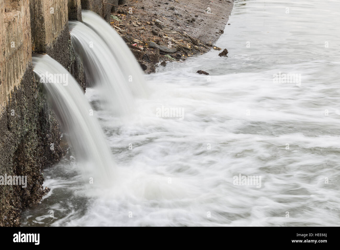 Water flowing from drain to the river Stock Photo - Alamy