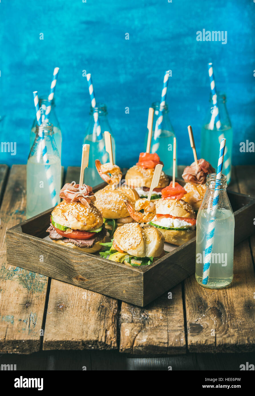 Different burgers with sticks in wooden tray and fresh lemonade Stock ...