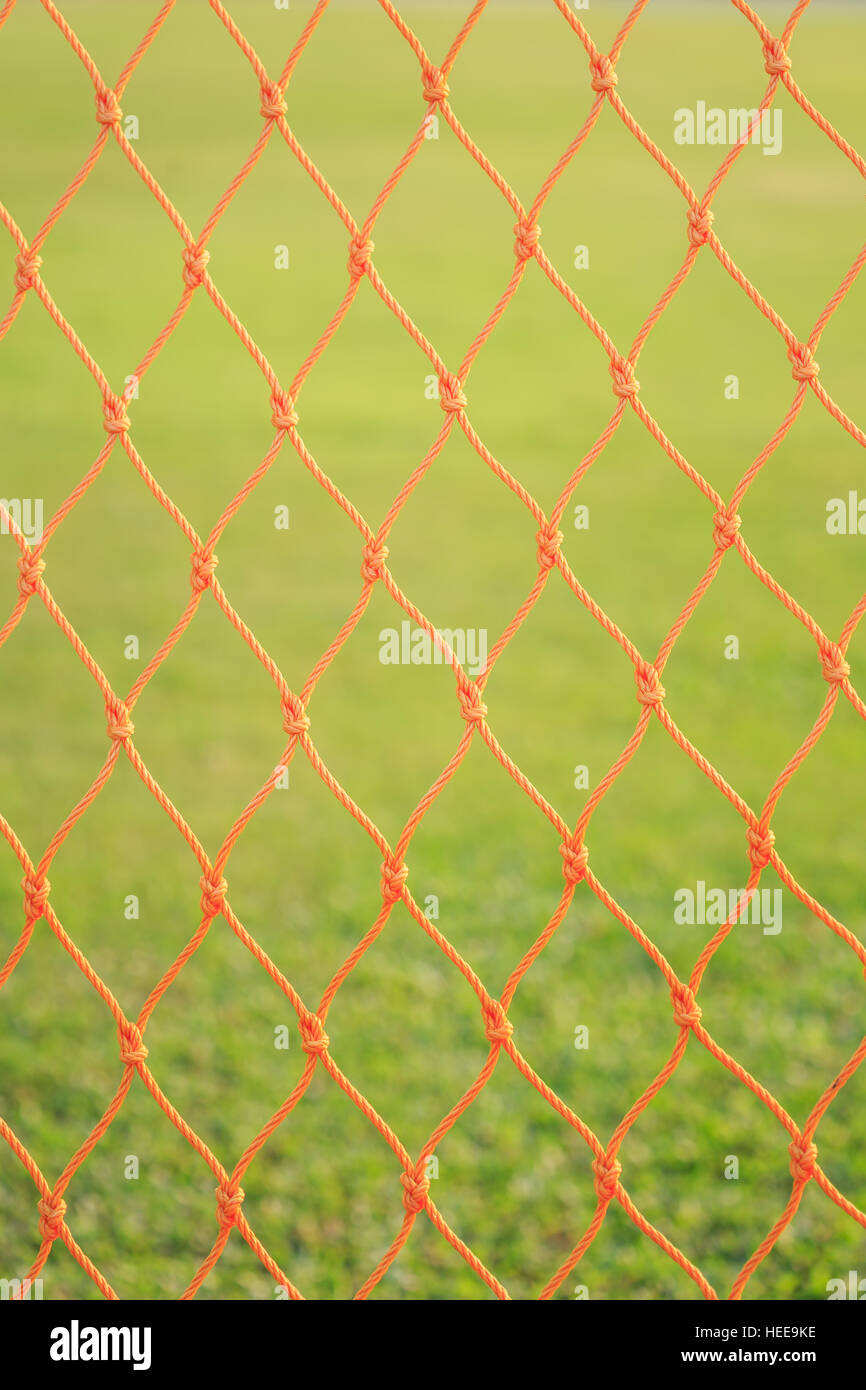 Close up orange soccer net on green grass background Stock Photo - Alamy