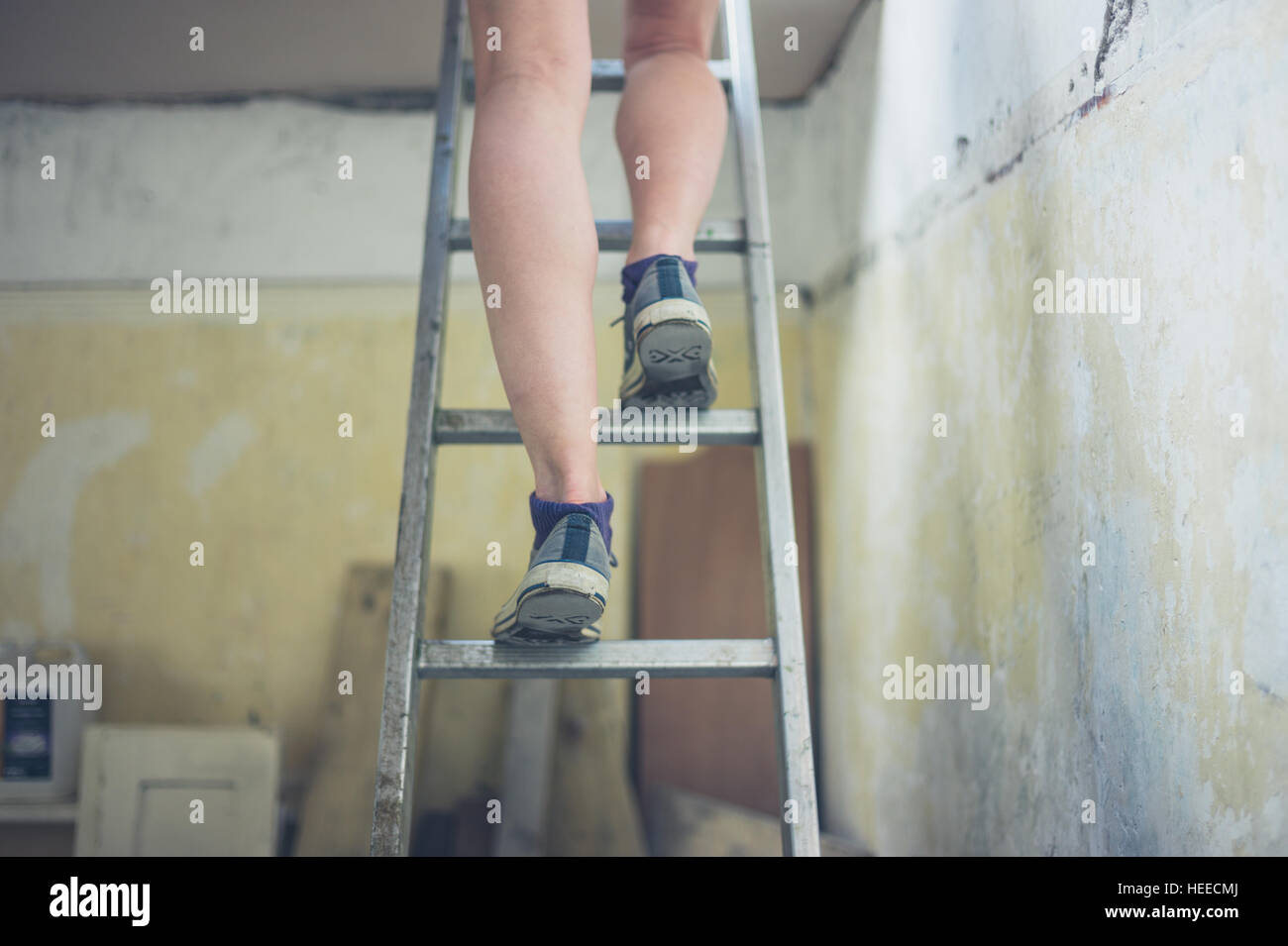 The legs of a young woman standing on a ladder to the loft Stock Photo ...