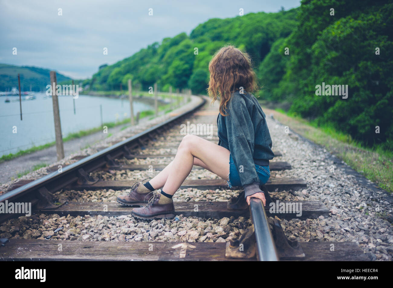 A young woman is sitting on the railroad tracks Stock Photo - Alamy