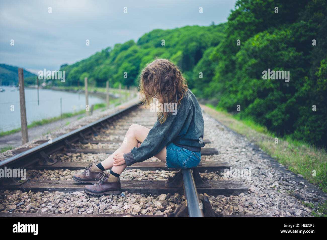 A young woman is sitting on the railroad tracks Stock Photo - Alamy