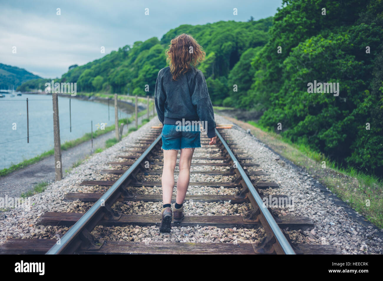 A young woman is walking on the railroad tracks Stock Photo - Alamy