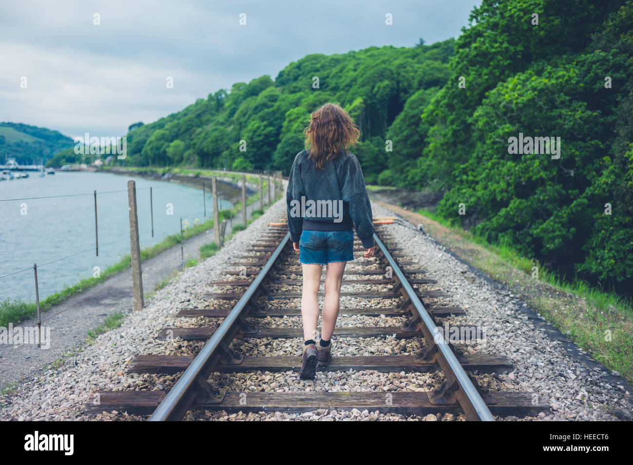 A young woman is walking on the railroad tracks Stock Photo - Alamy