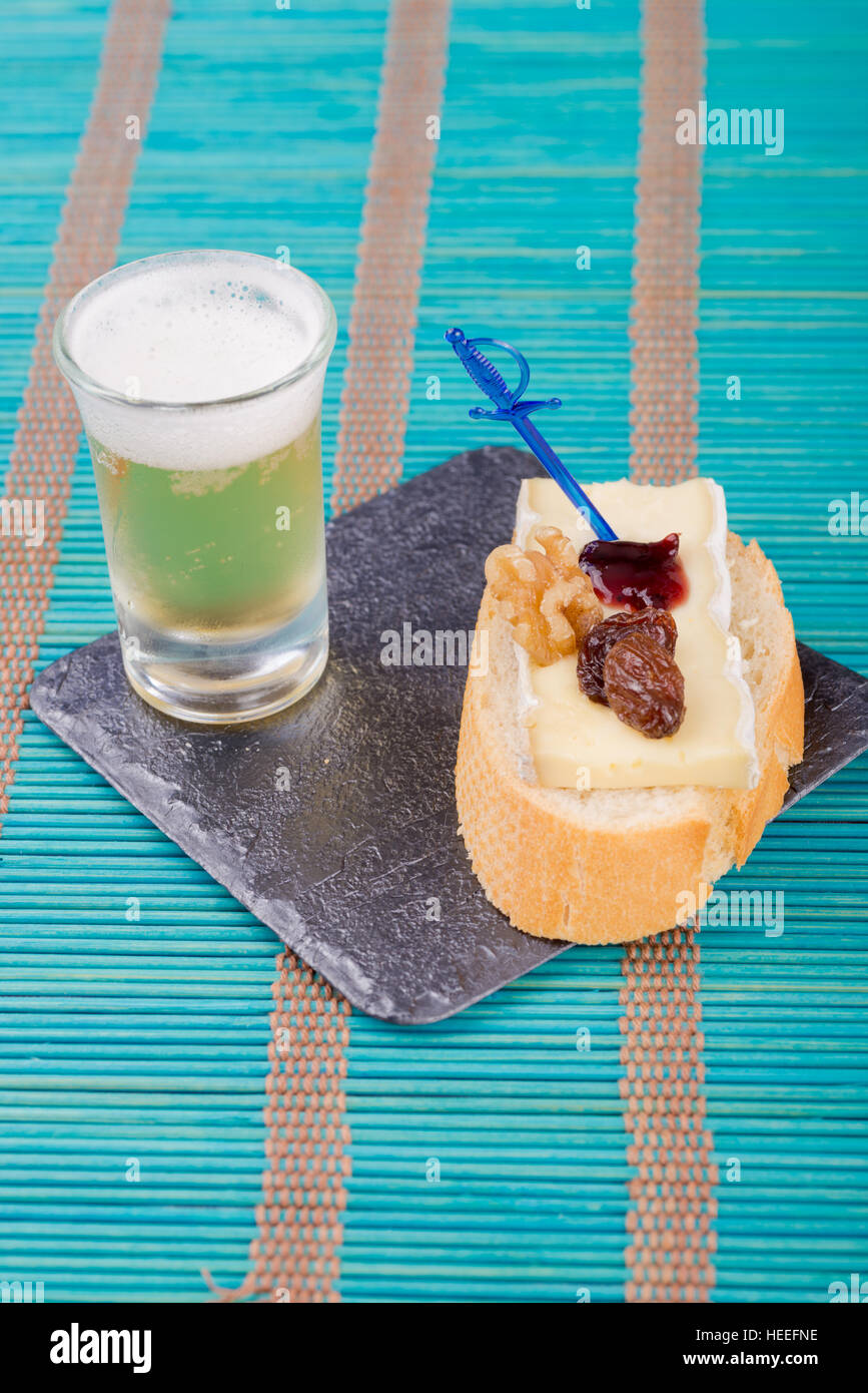 Cheese tapa served as pincho on bread with a small glass of beer Stock ...