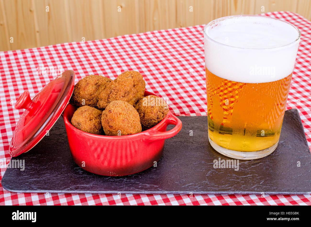 Portion of freshly fried cod fish croquettes served with beer, a ...