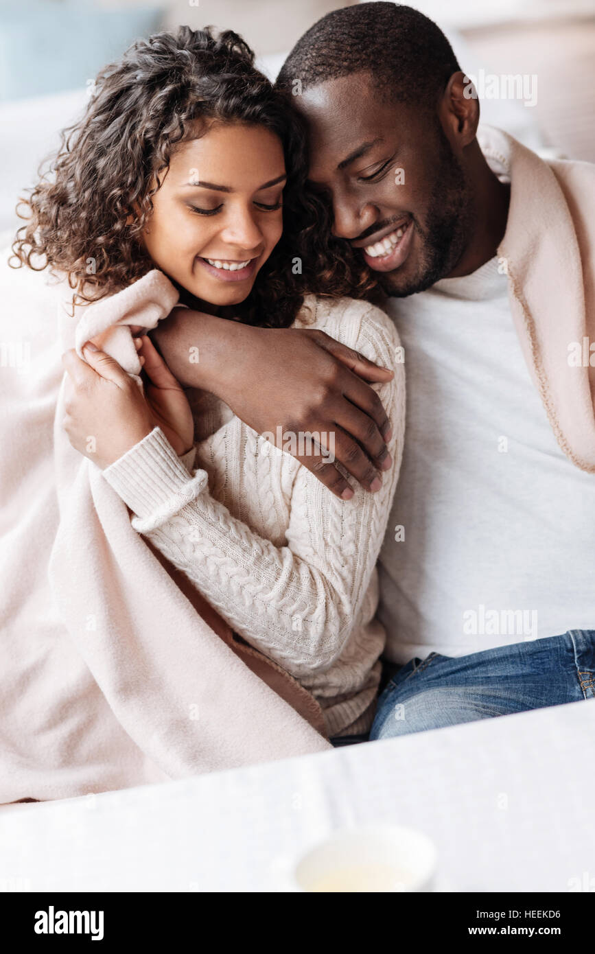 Delighted young African American couple sitting and hugging Stock Photo ...