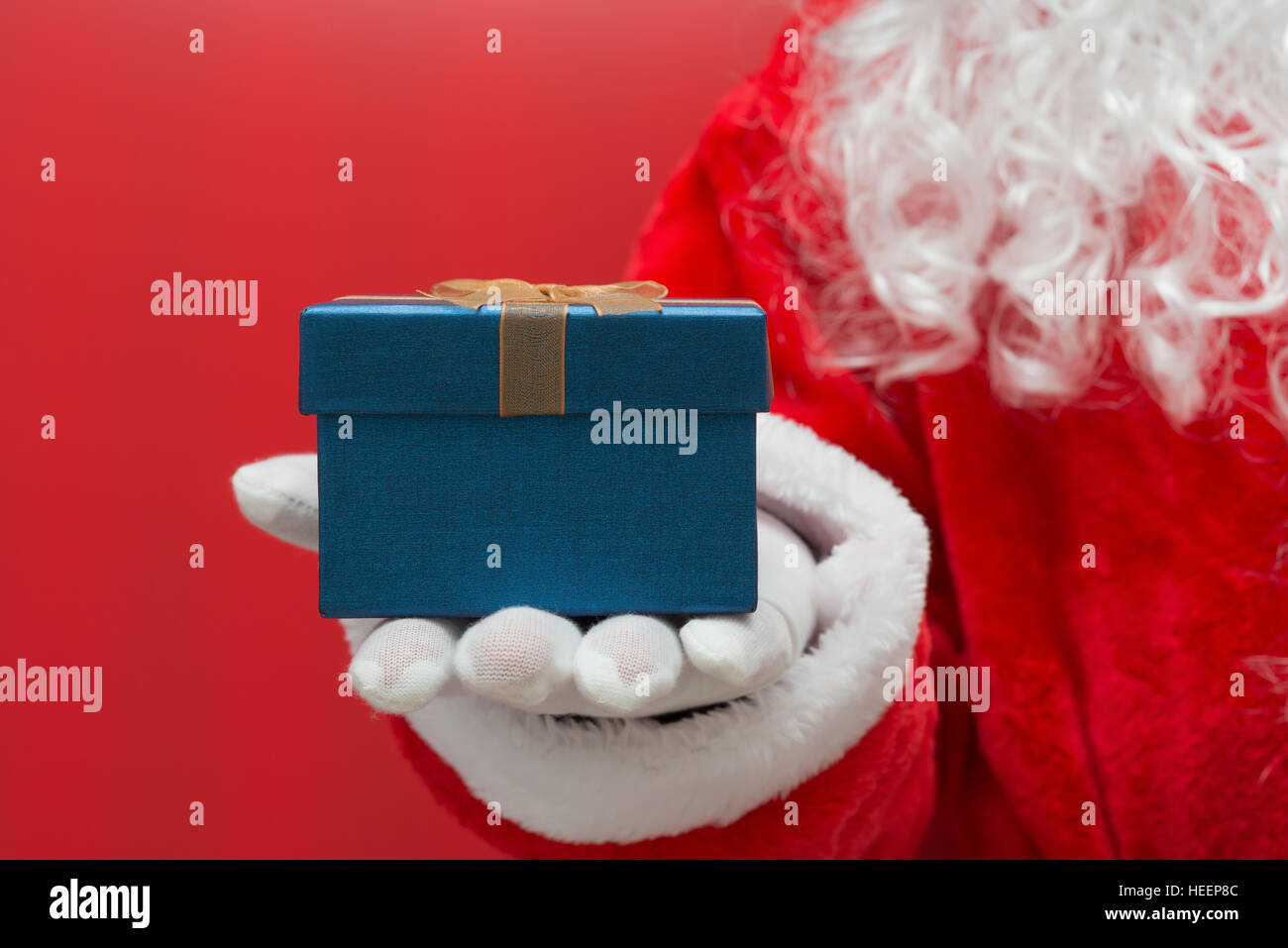 Santa Claus handing a Christmas Gift box over red background Stock ...