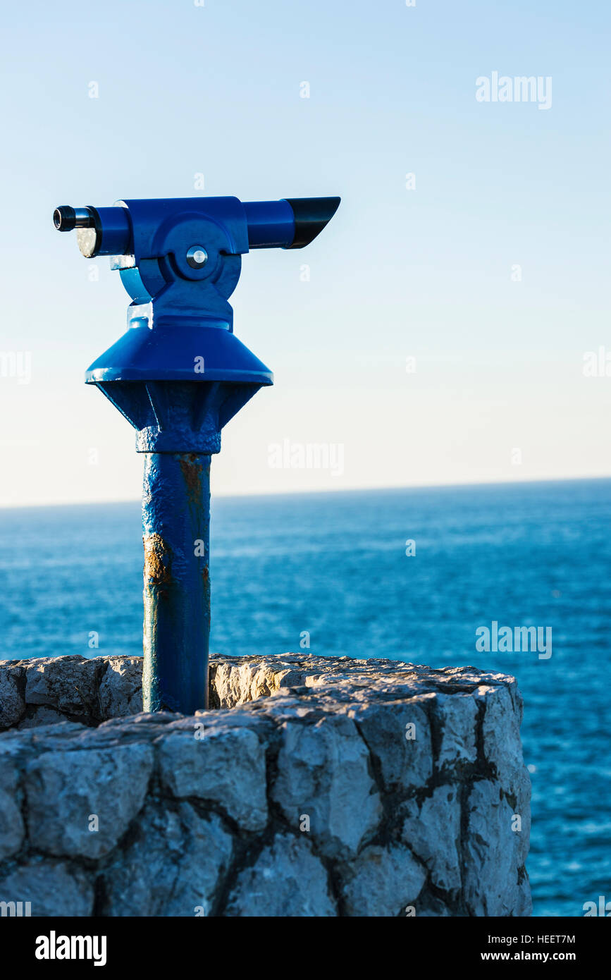 Blue panoramic telescope on a stone turret with the sea as background ...