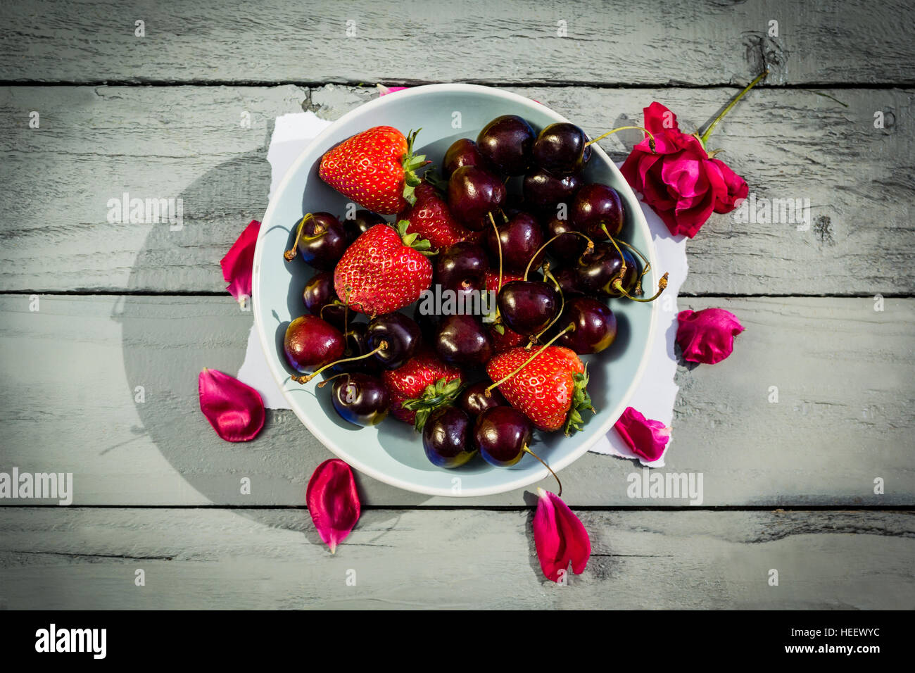 A bowl of cherries red roses on wooden background Stock Photo - Alamy
