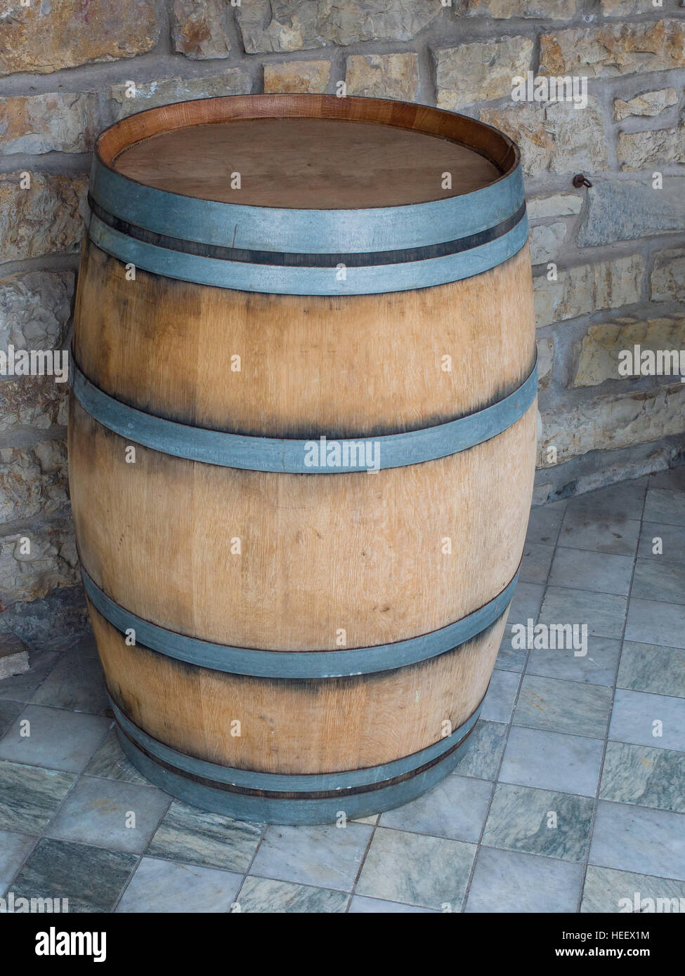 wooden barrel with iron rings on a marble tile floor, rough stone wall ...