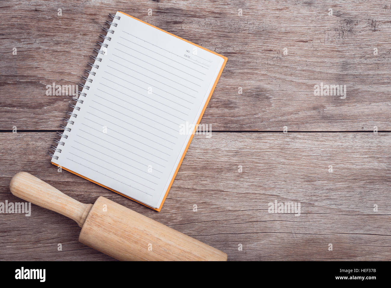 Close up wooden rolling pin and lined paper on wooden table top view ...