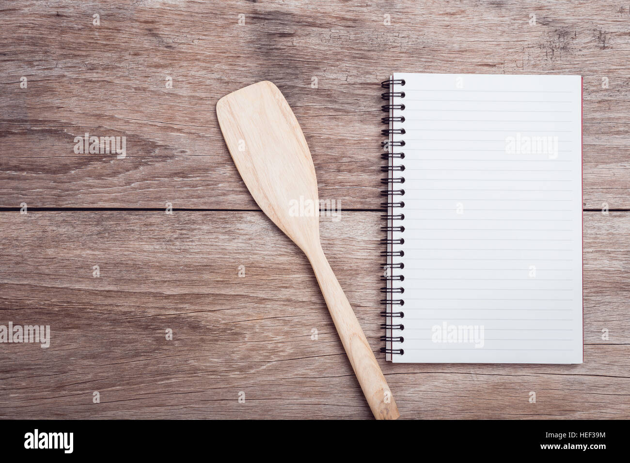 Close up cooking wooden spatula and lined paper on wooden table top ...