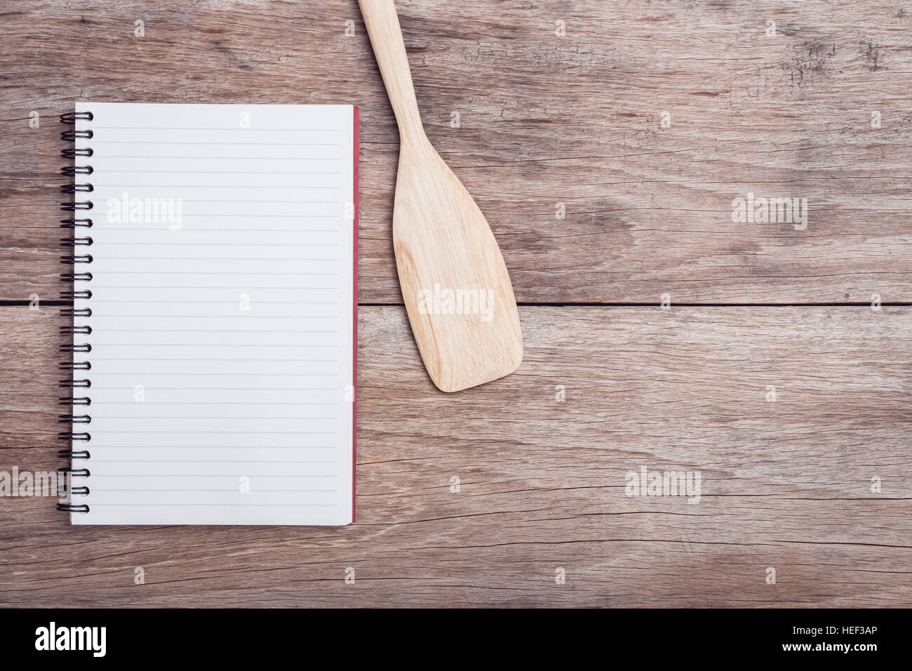 Close up cooking wooden spatula and lined paper on wooden table top ...