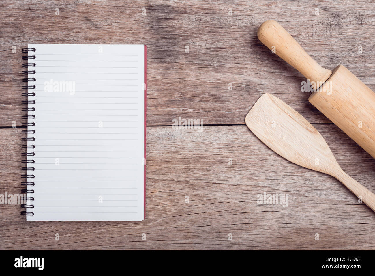 Close up cooking wooden spatula, rolling pin and lined paper on wooden ...