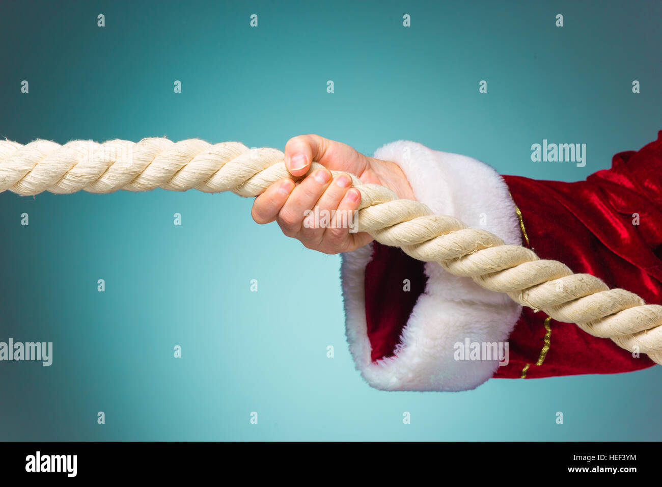 Hand of Santa Claus pulling the rope on blue background Stock Photo - Alamy