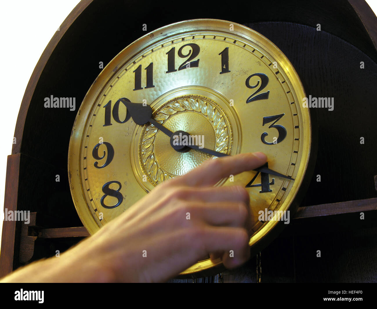 Human hand changes time on the old clock, moving it forward in time ...