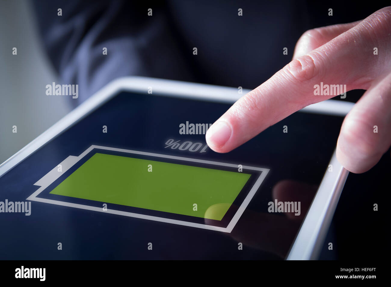 finger touches digital tablet showing full battery on screen Stock ...