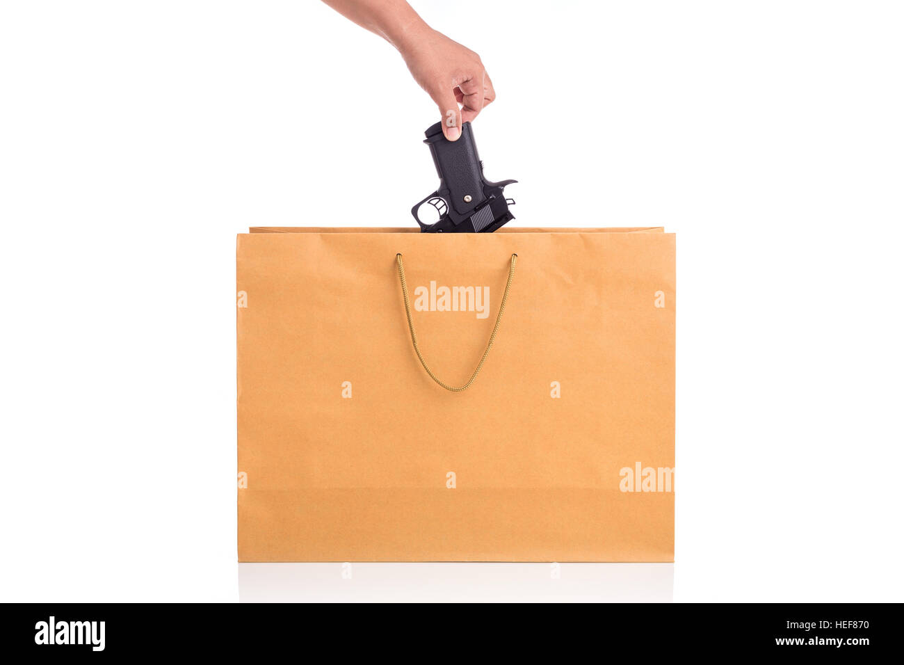 Close up hand holding gun in brown paper bag isolated on white ...