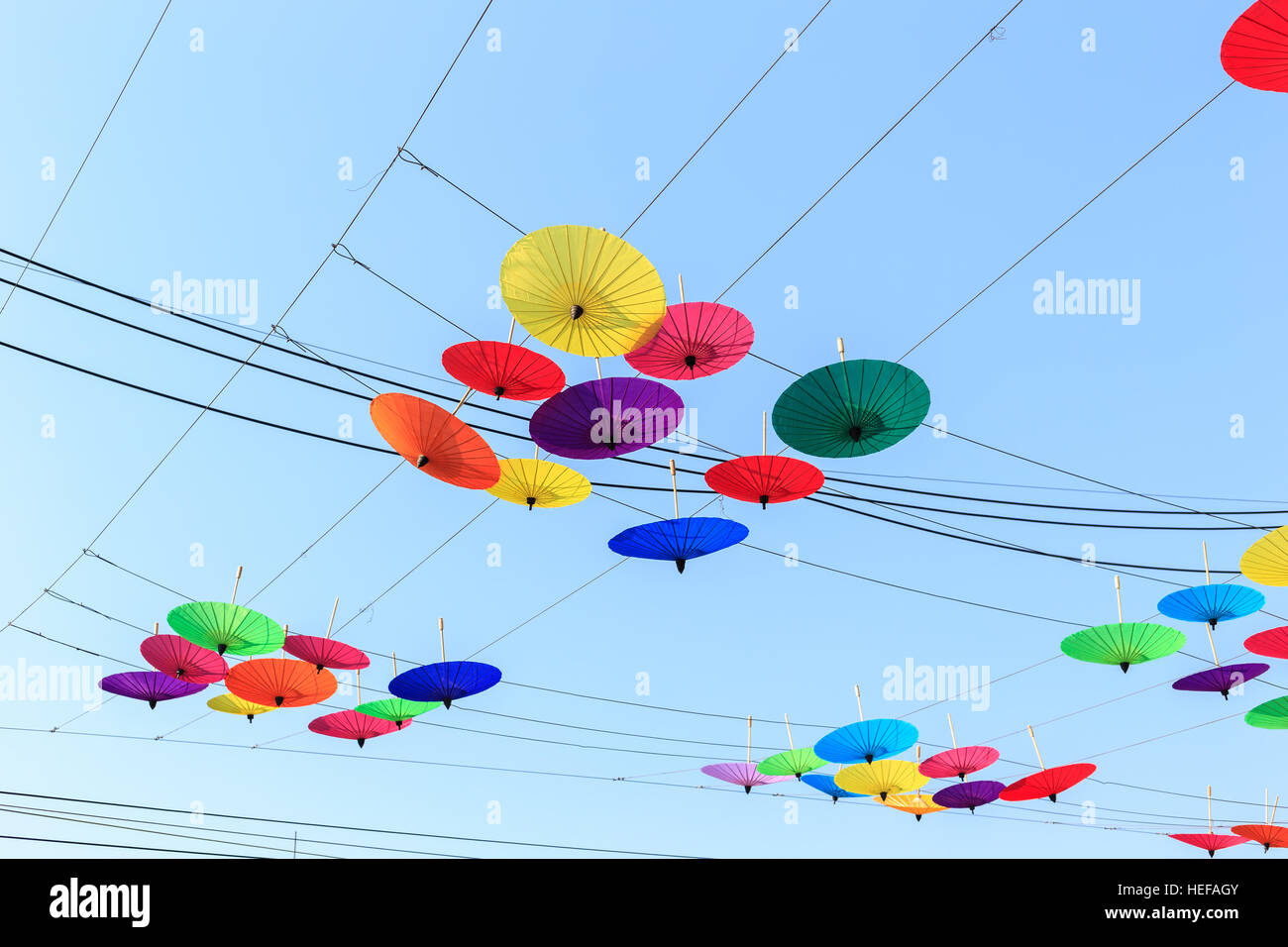 Colorful handmade umbrella hang on electric cable and sky background ...