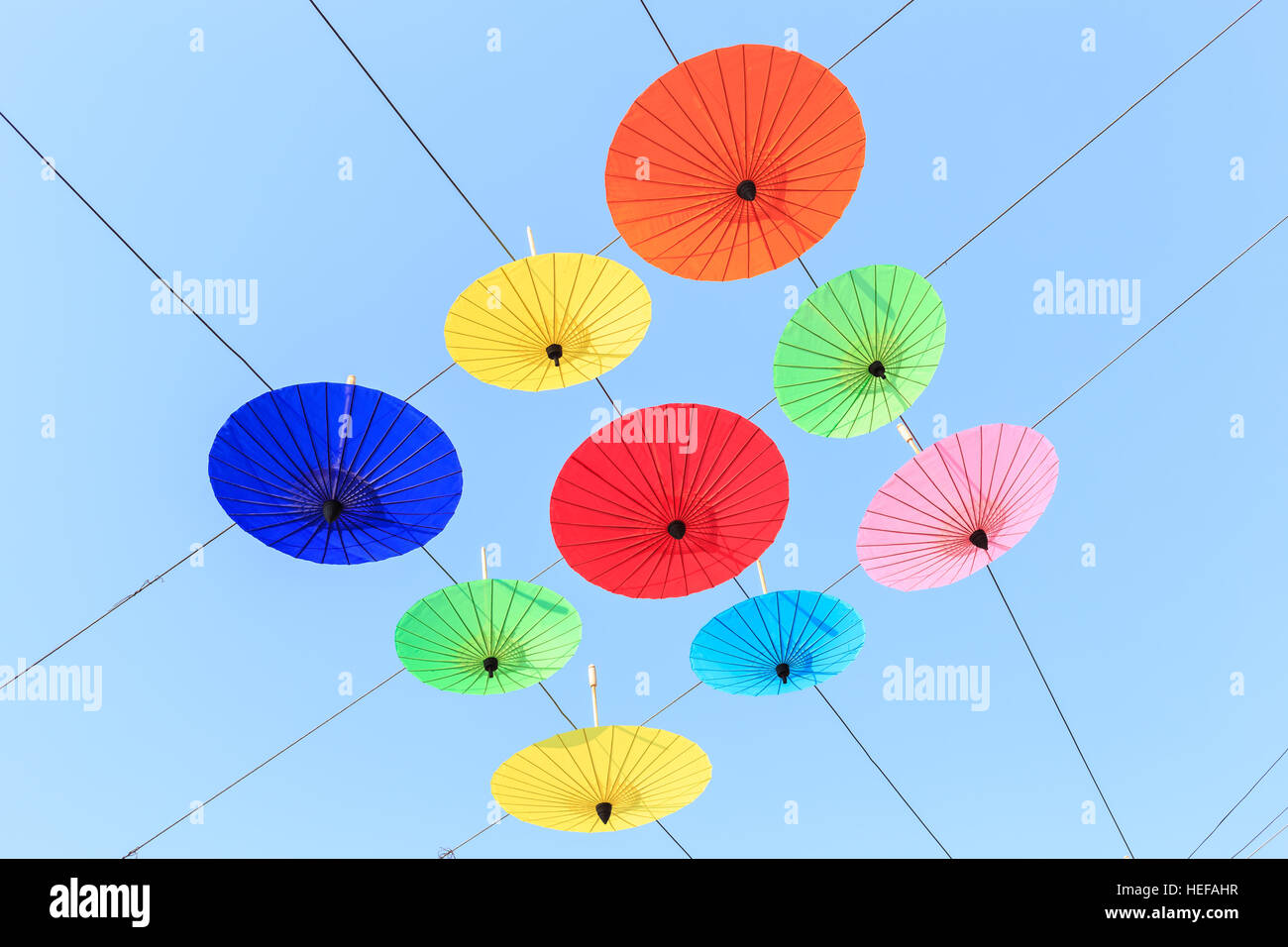 Colorful handmade umbrella hang on electric cable and sky background ...