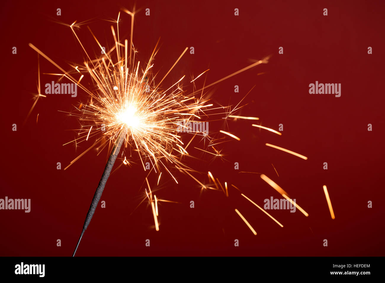 Burning sparkler on red background Stock Photo - Alamy