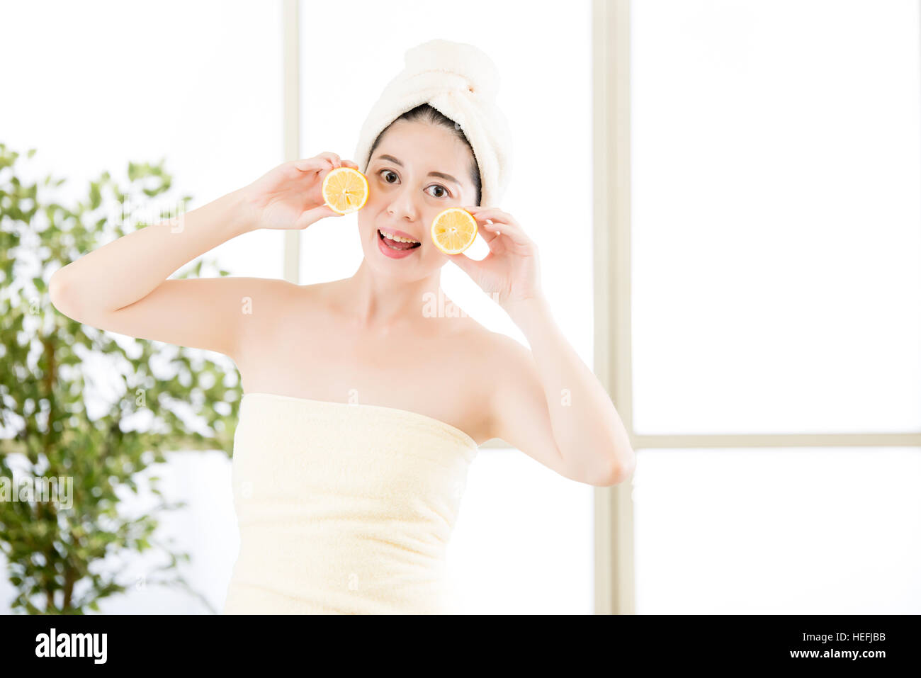 Woman with clean face holding slices of lemon over face. Lemon for ...