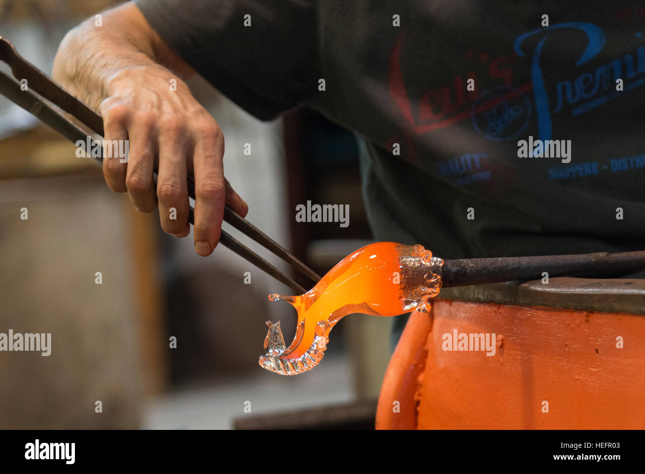 Man working with molten glass using a tweezers in glass factory, Murano ...