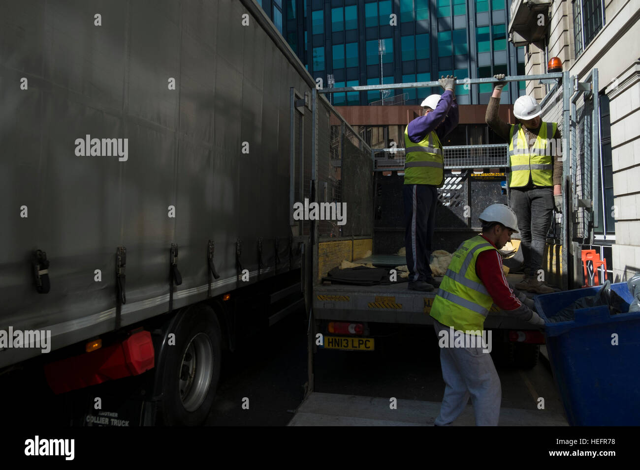 Workmen loading a lorry within street scene of light and shadow in the ...