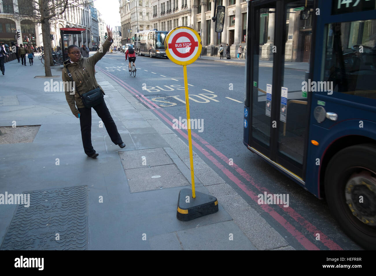 Street scene of a woman flagging a bus at a temporary bus stop in the ...