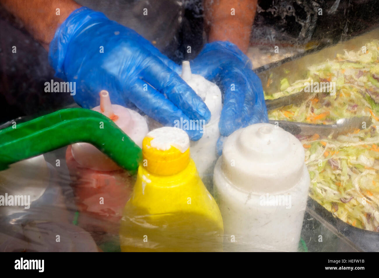 Chef wearing blue gloves during food preparation at a street food stall ...