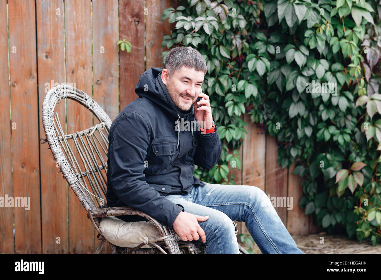 Handsome man relax in vintage rocking-chair with phone in garden Stock ...