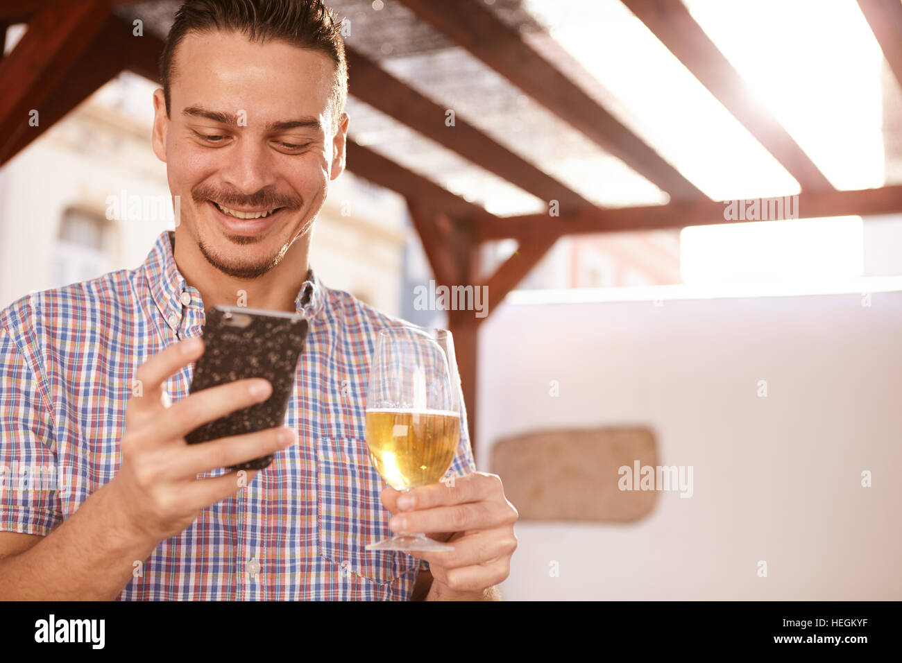 Good looking guy grinning with great satisfaction at his cellphone with ...