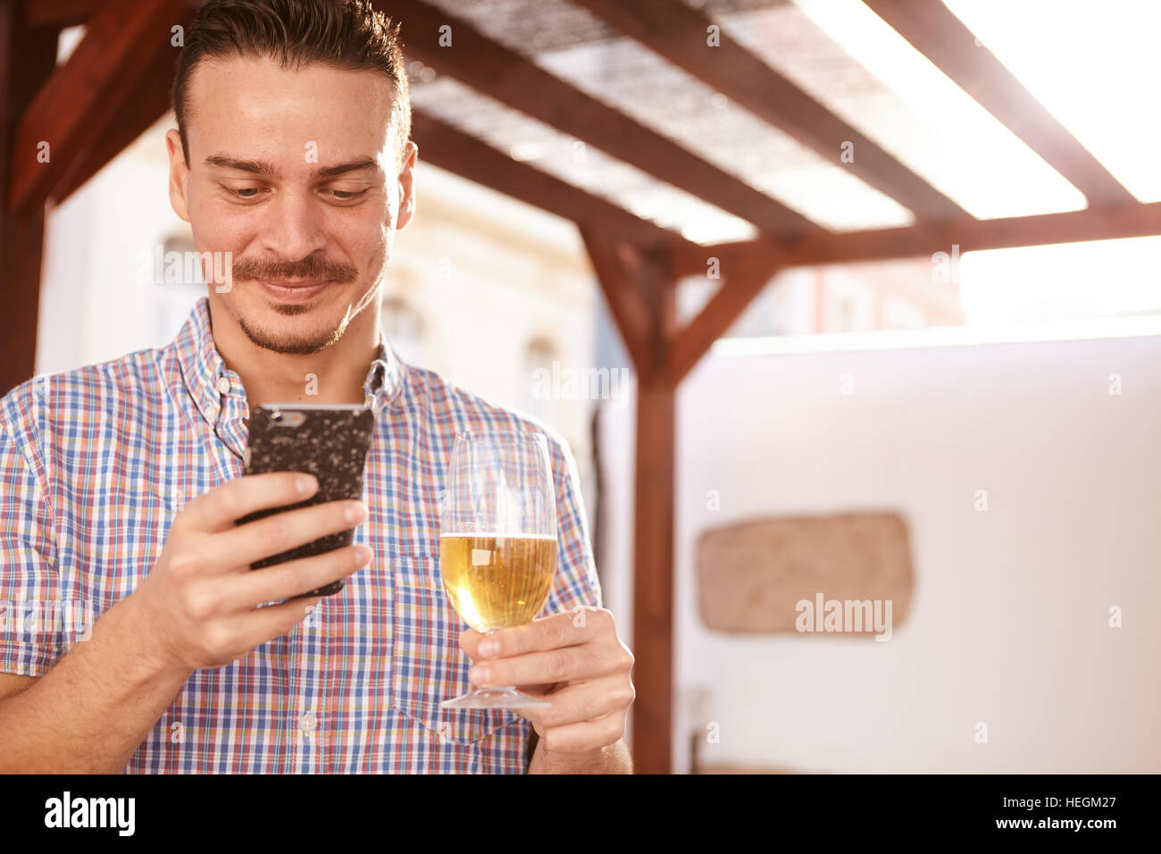 Handsome man looking at his cellphone with a secretive smile while ...