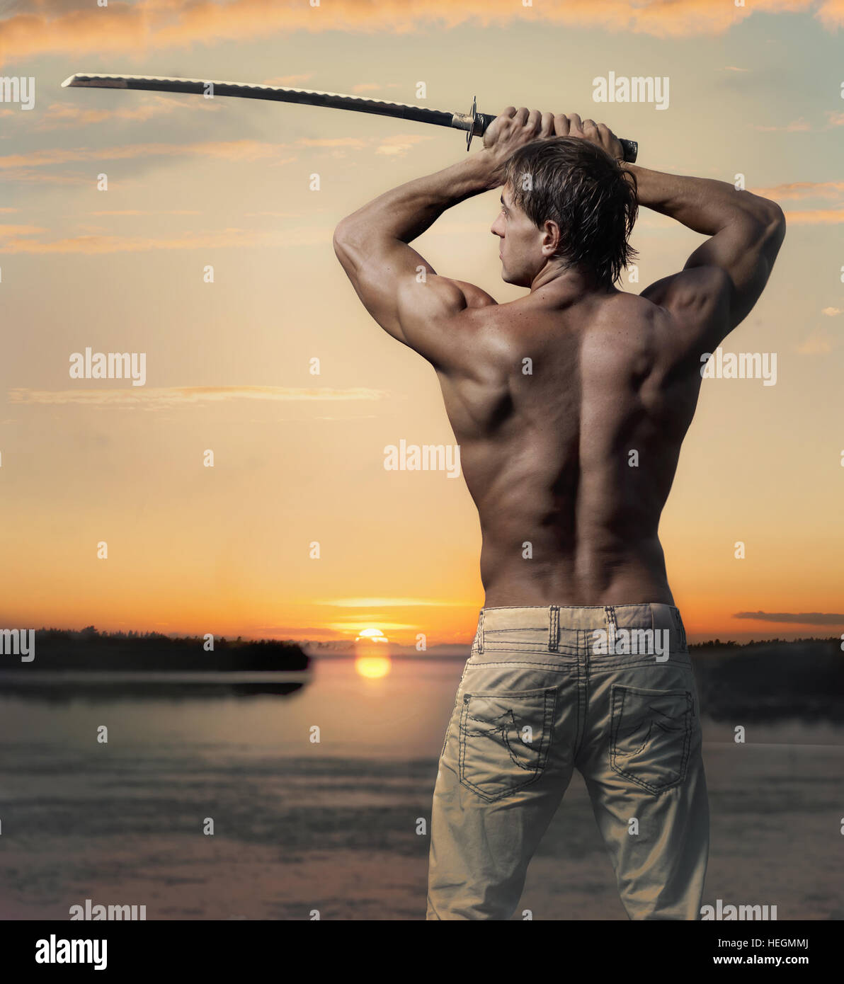 Muscular handsome guy with sword at sunset Stock Photo - Alamy