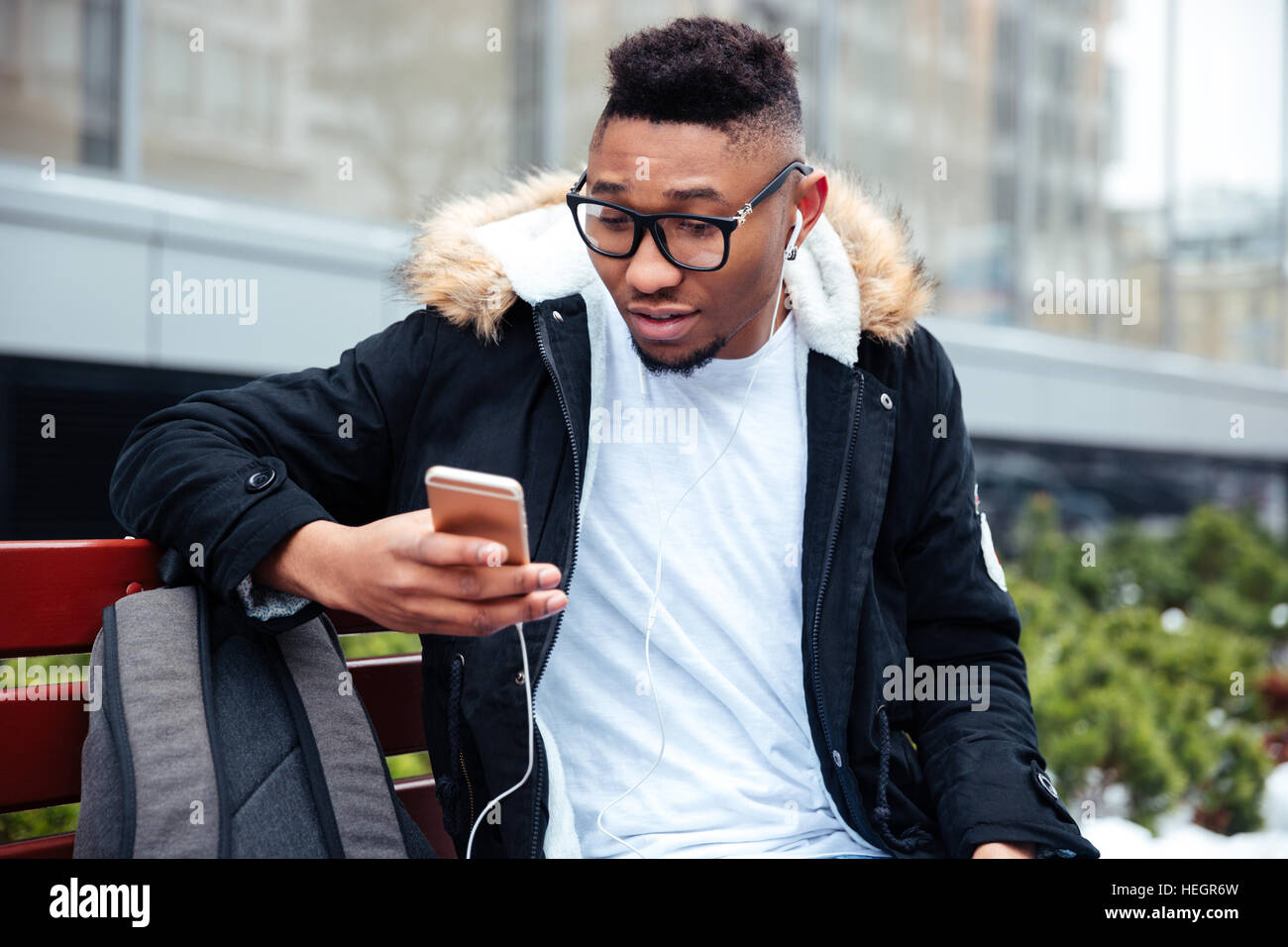 Photo of african man holding his cellphone in hands and chatting while ...
