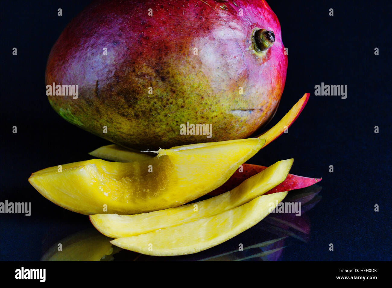 Sliced mango with bite taken. Black background Stock Photo - Alamy