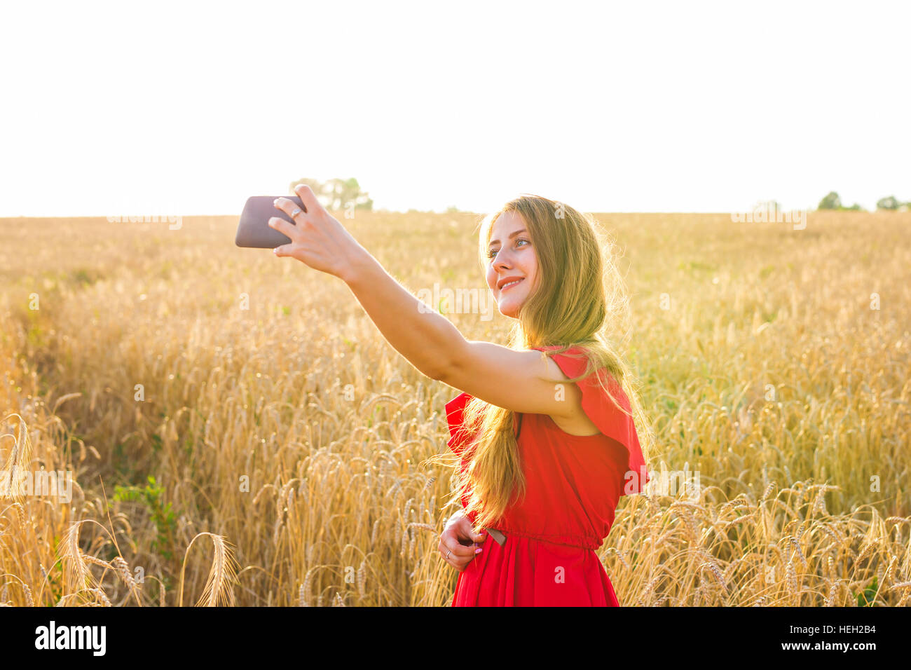 Beautiful woman taking selfie picture of herself in yellow field with ...