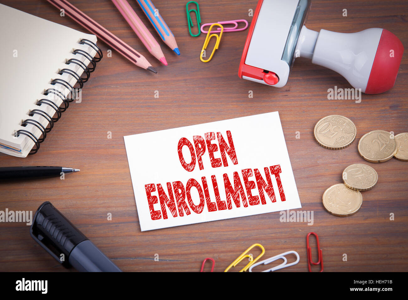 Open Enrollment. Wooden office desk with stationery, money and a note ...