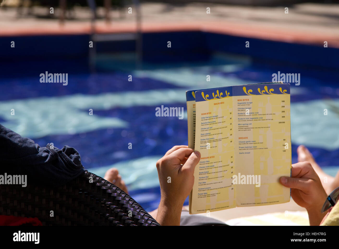 A tourist looking at a food menu next to the pool area in a hotel in ...