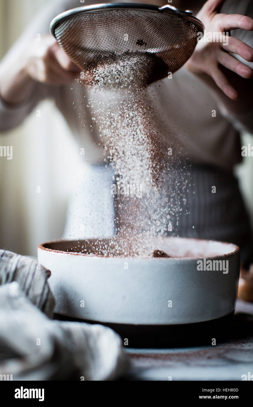 Woman sprinkling flour in to a mixing bowl Stock Photo - Alamy