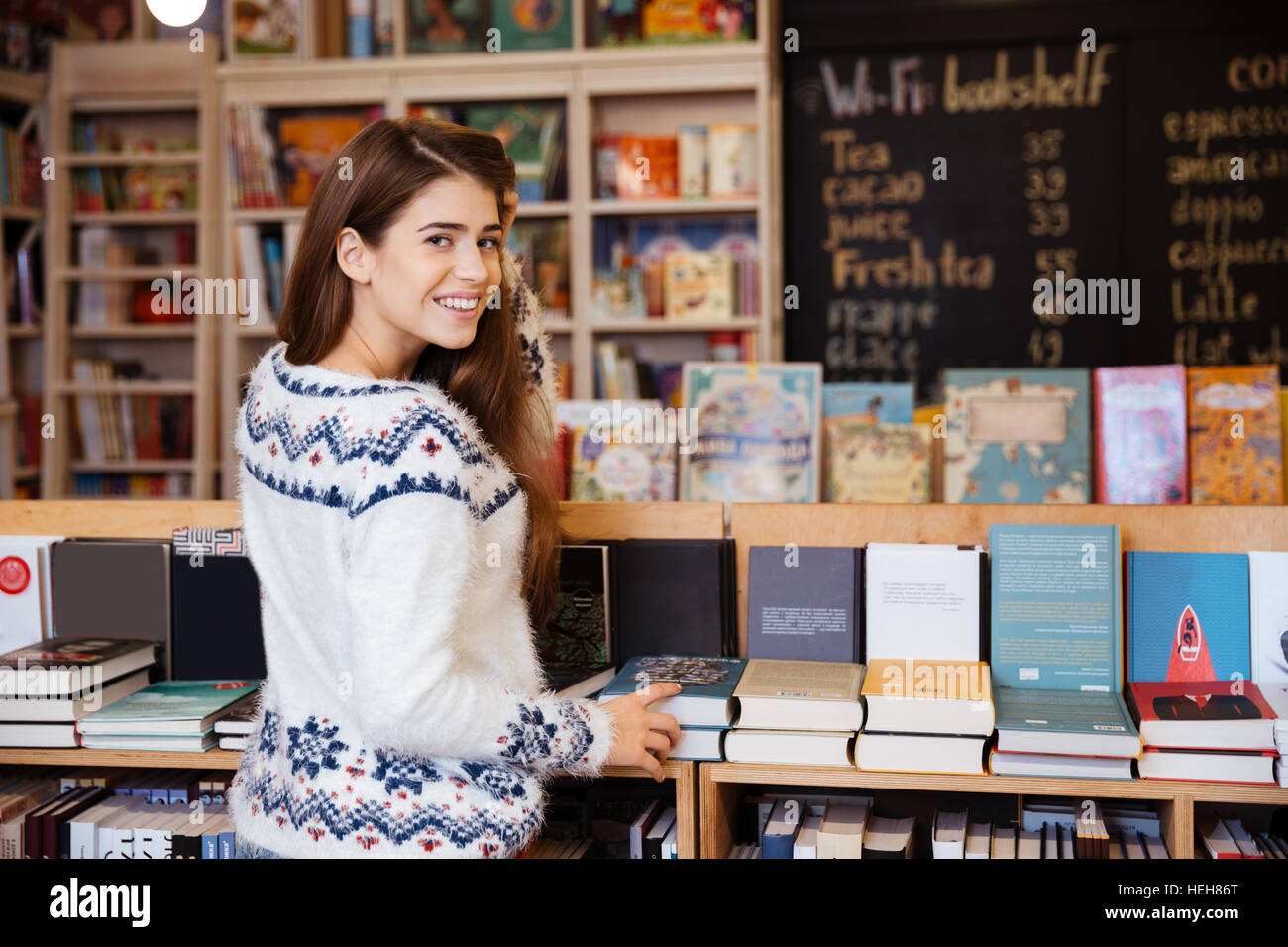 Back view portrait of a pretty young woman choosing books in library ...