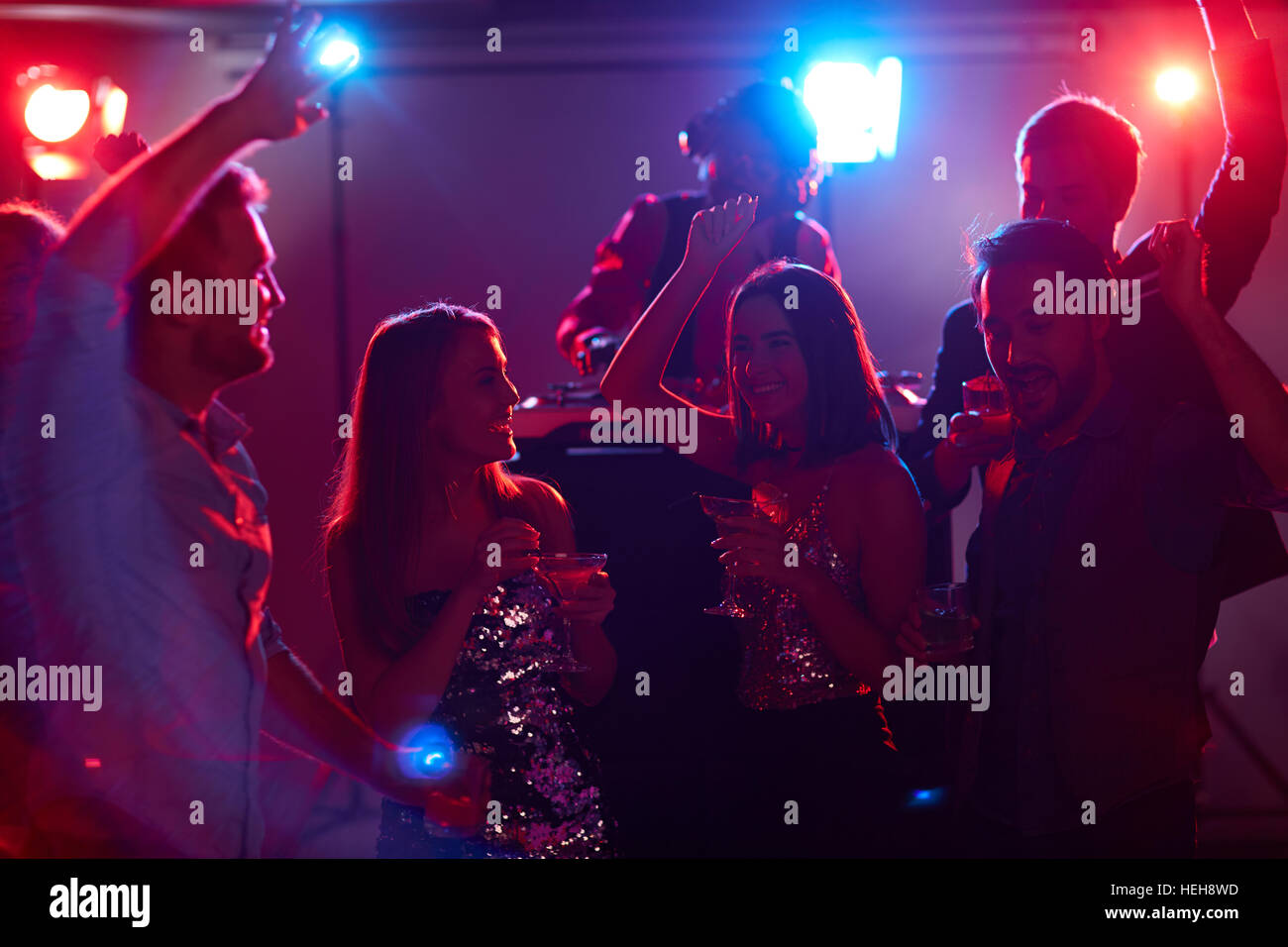 Joyful friends with cocktails talking and dancing at disco party Stock ...