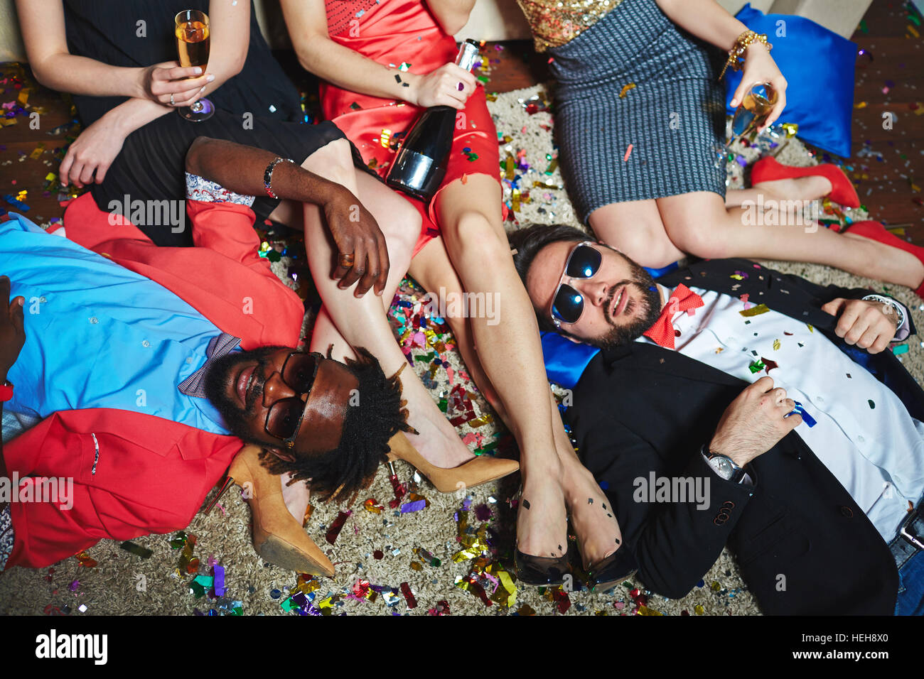Tired men lying on the floor at party with group of beautiful girls ...