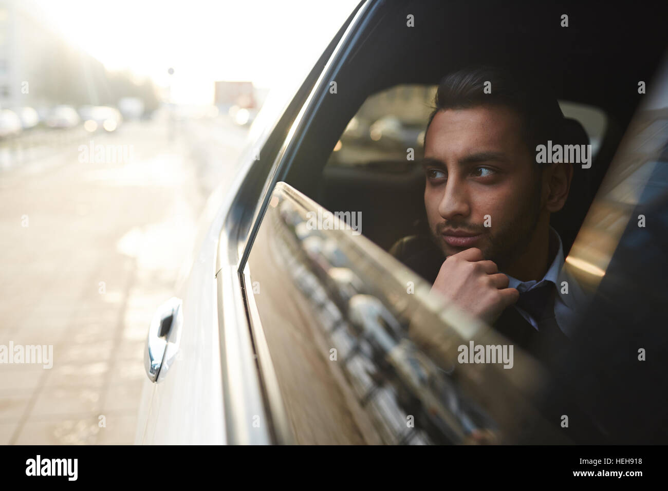 Wealthy man looking through car window while traveling in the city ...
